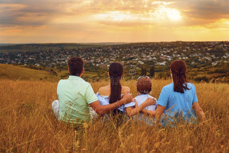 Familia Que Se Sienta En La Naturaleza Que Mira Puesta Del Sol Hermosa ... Familia Que Se Sienta En La Naturaleza Que Mira Puesta Del Sol Hermosa ...