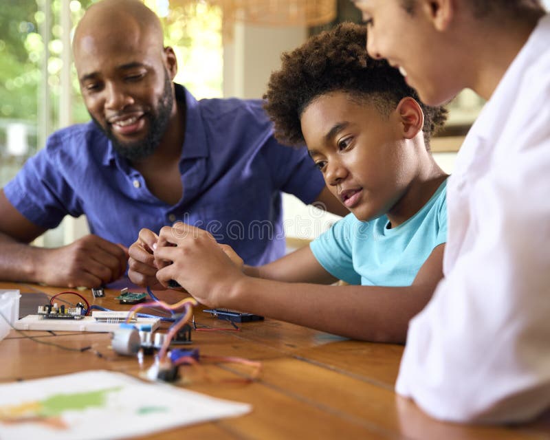 Family Around Table at Home Using Laptop with Parents Helping Son with ...