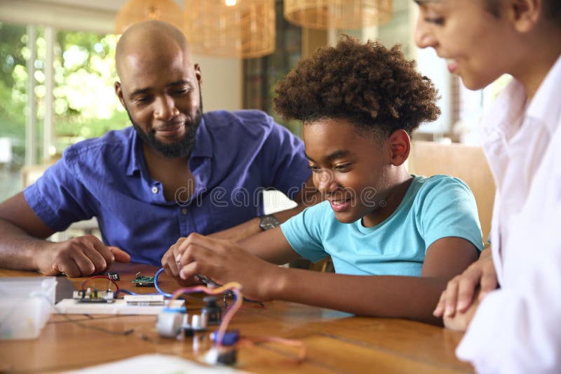 Family Around Table at Home Using Laptop with Parents Helping Son with ...