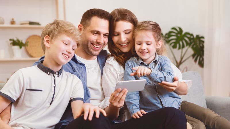 Family of Four Using Smartphone Sitting on Couch at Home Stock Photo ...