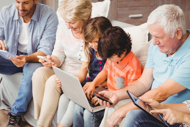 Family with Grandparents Using Technology while Sitting on Sofa Stock ...