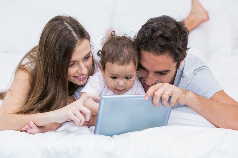 Family Looking at Digital Tablet on Bed Stock Image - Image of indoors ...