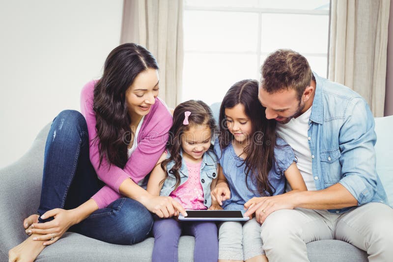 Family Looking in Tablet Computer while Sitting on Sofa Stock Image ...