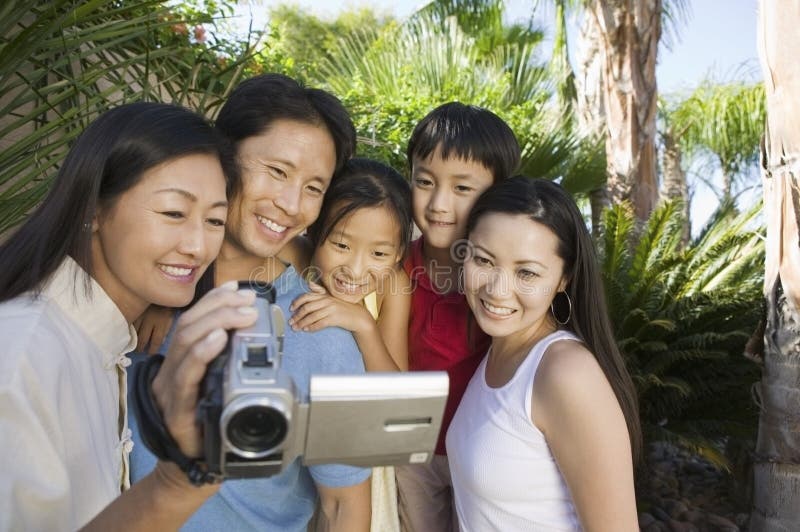 Family Looking at Video Camera Screen in Back Yard Front View Stock ...