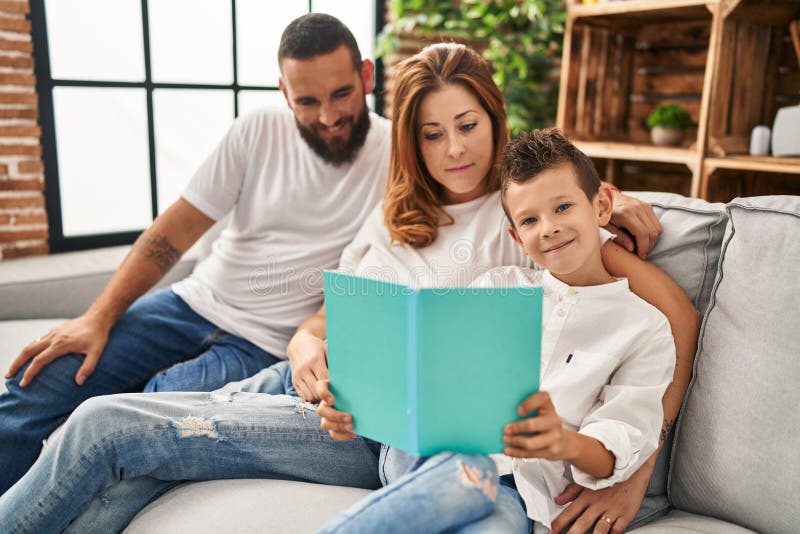 Family Reading Book Sitting on Sofa at Home Stock Photo - Image of ...