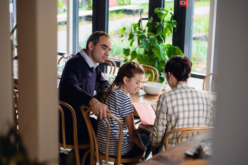 A Family Reading Something at the Kitchen Table, View from the Back ...