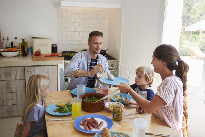 Family Sitting Around Kitchen Table Serving Lunch Stock Photo - Image ...