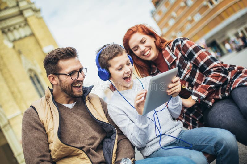 Family Sitting on Bench, Relaxing Using Gadget, Browsing Internet Stock ...