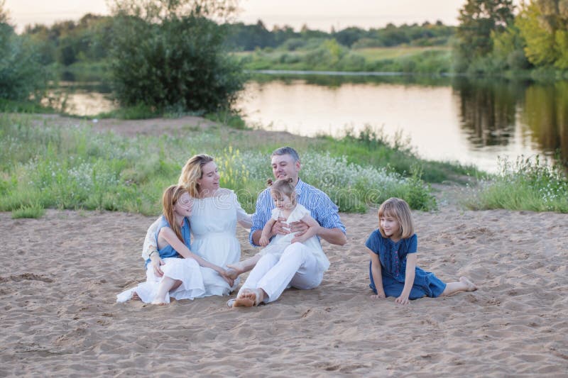 Family Sitting on Sand by River Stock Photo - Image of grass, green ...