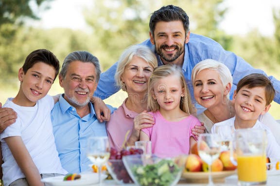Family Sitting at Table Outdoors, Smiling Stock Photo - Image of ...