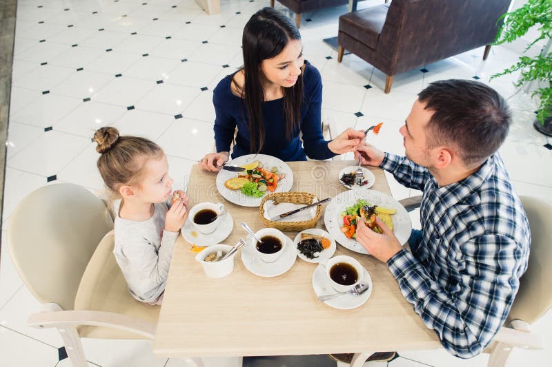 Family Sitting Together at Table in a Restaurant Stock Photo - Image of ...