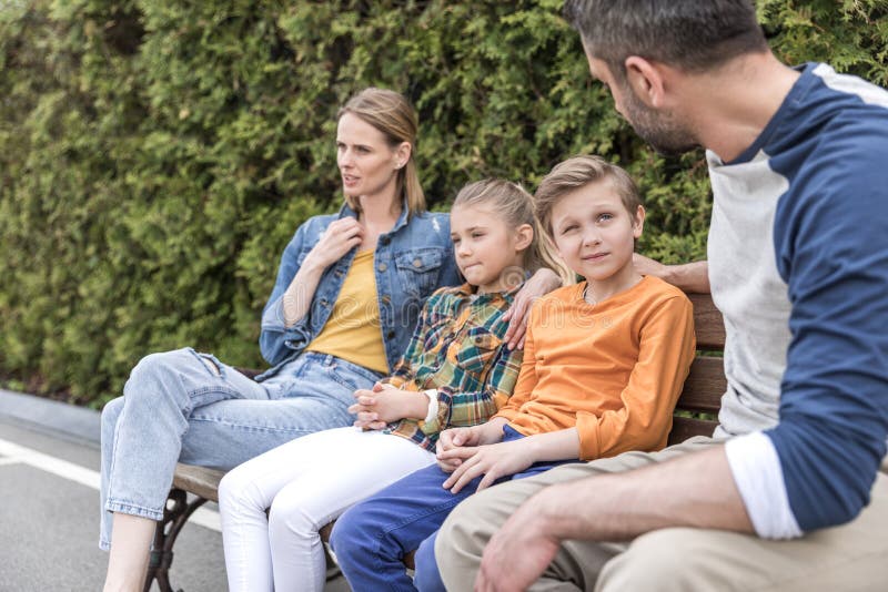 Family Talking while Sitting Together on Bench at Park Stock Photo ...