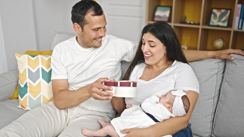 Family of Three Giving a Present Sitting on the Sofa at Home Stock ...
