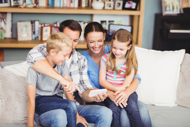 Family Using Mobile Phone while Sitting on Sofa Stock Image - Image of ...