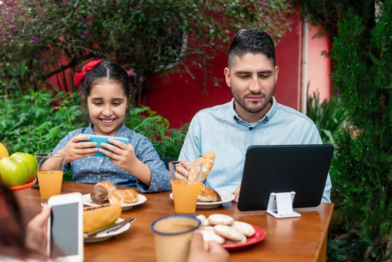 Family Using Mobile, Tablet and Having Breakfast in Table Outside Stock ...