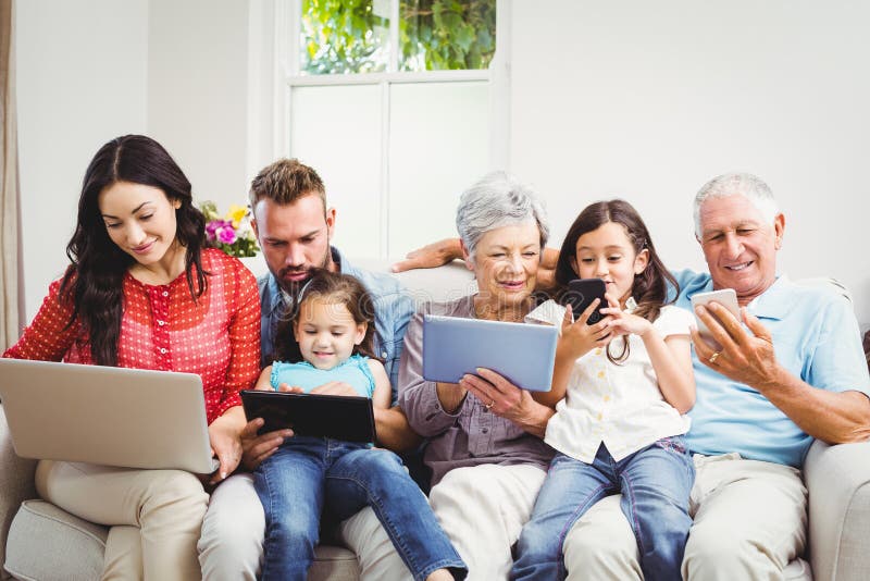 Family Using Technologies while Sitting in Sofa Stock Image - Image of ...