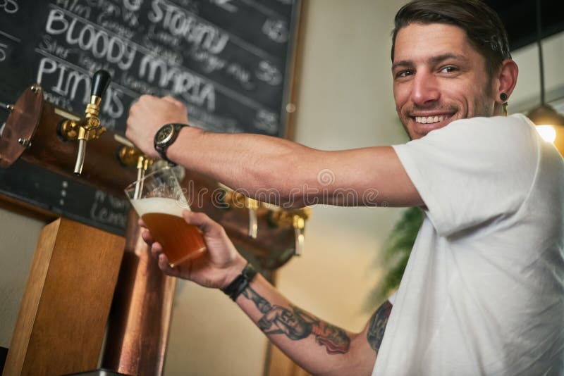 Fancy a Cold One. Portrait of a Young Bartender Pouring Beer from a Tap ...
