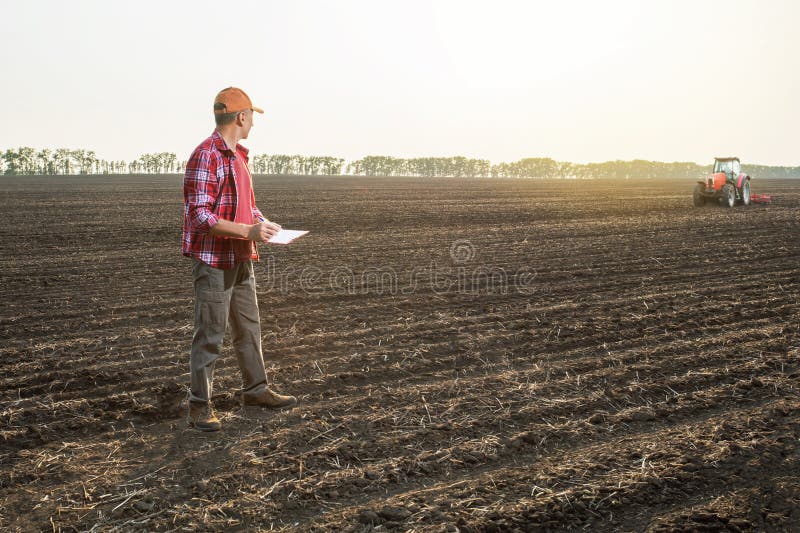 Farmer Man with Notebook in Field with Tractor. Stock Photo - Image of ...