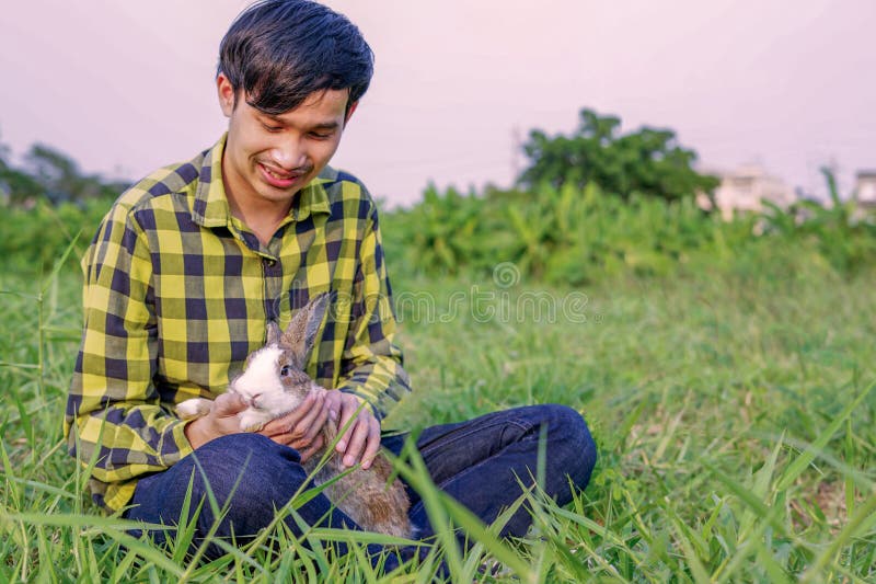 Farmer Taking Care of a Young Cute Rabbit in the Field Stock Photo ...