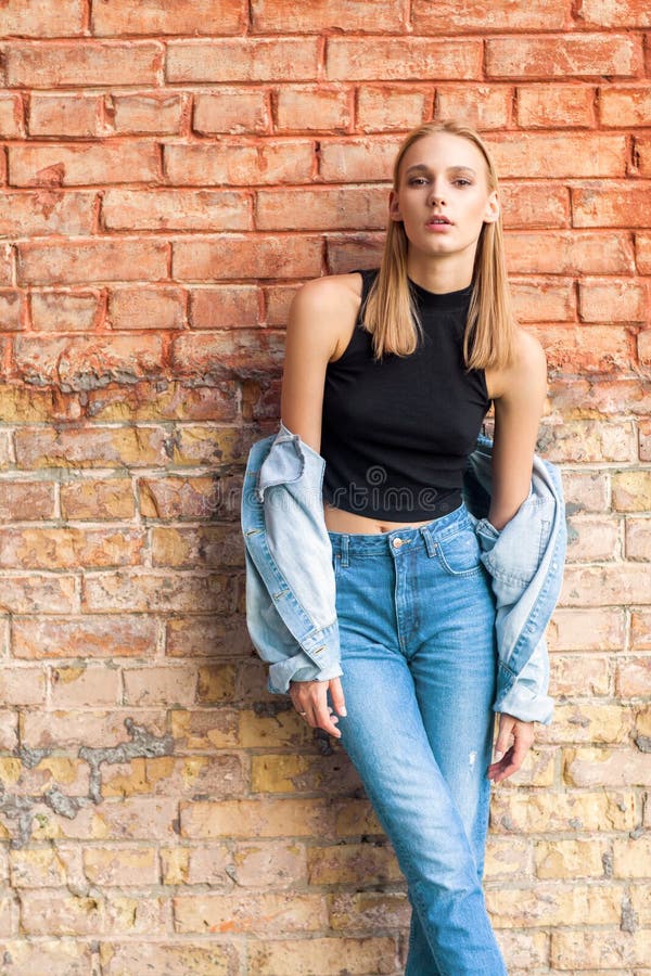 Fashion Girl Standing Near Brick Wall In Denim And Sneakers Vogue