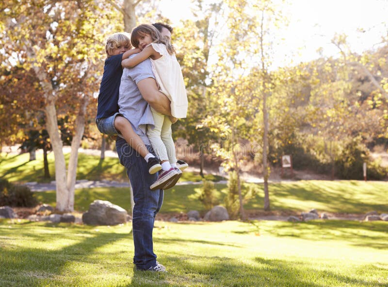 Father Carrying Son and Daughter As they Play in Park Stock Photo ...