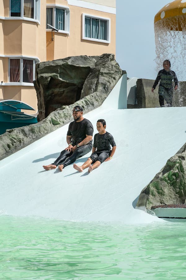 Father and Children Sliding into Pool after Going Down Water Slide ...