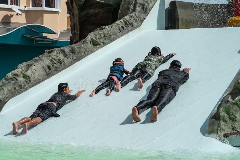 Father and Children Sliding into Pool after Going Down Water Slide ...