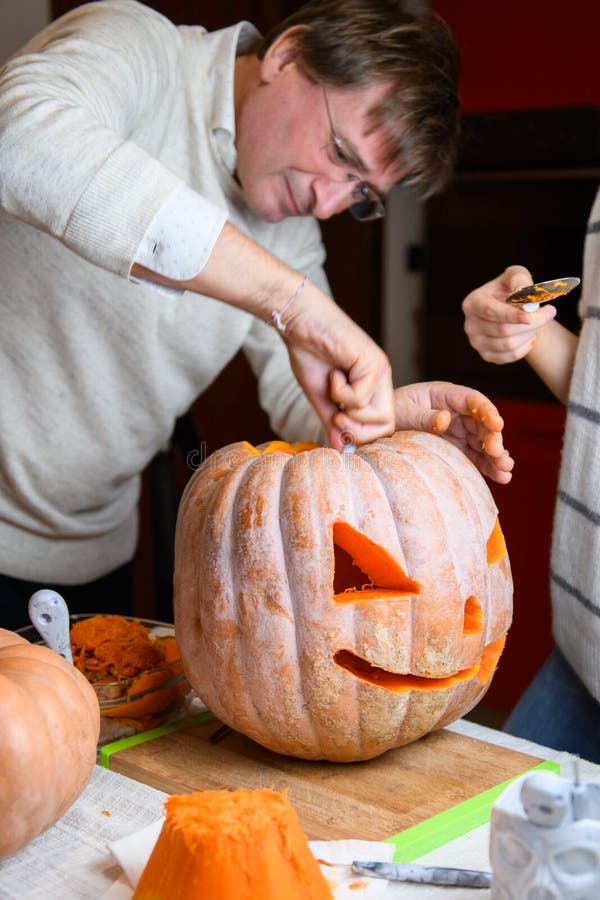 Father And Daughter Carving Pumpkin Jack O Lanterns On Halloween Party