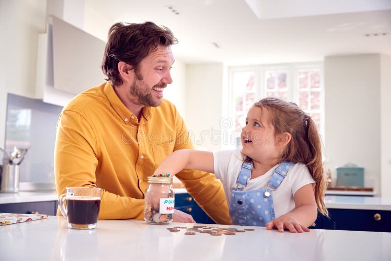 Father and Daughter Counting Pocket Money in Jar on Kitchen Counter ...