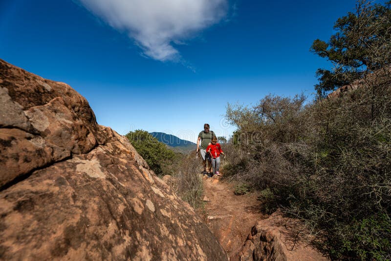 Father and Daughter Hiking on Rugged Mountain Trail Under Clear Blue ...