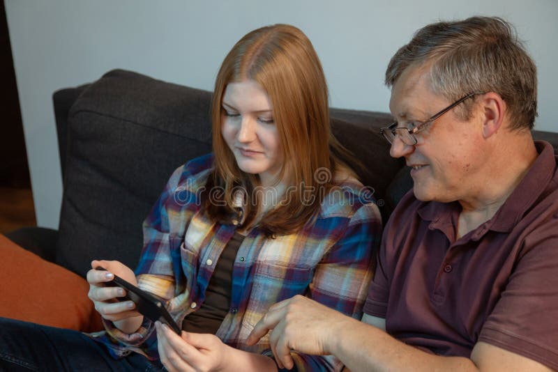 Father and Daughter Looking at Smartphone Screen on Sofa Stock Photo ...