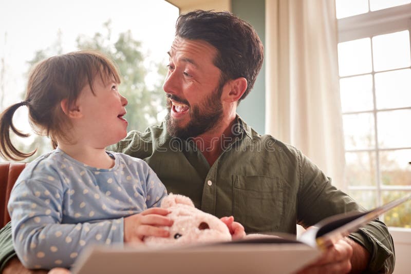 Father with Down Syndrome Daughter Reading Book at Home Together Stock ...