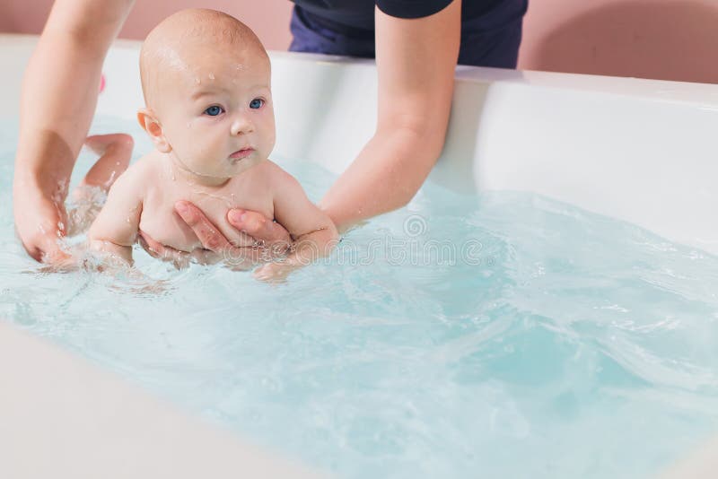 A Father Helps is Infant Boy during Swimming Lessons in the Pool. Stock ...