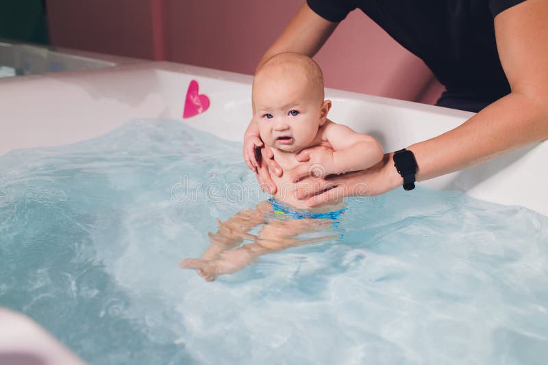 A Father Helps is Infant Boy during Swimming Lessons in the Pool. Stock ...