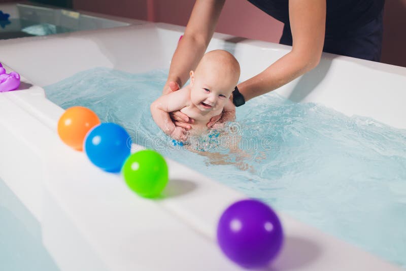 A Father Helps is Infant Boy during Swimming Lessons in the Pool. Stock ...