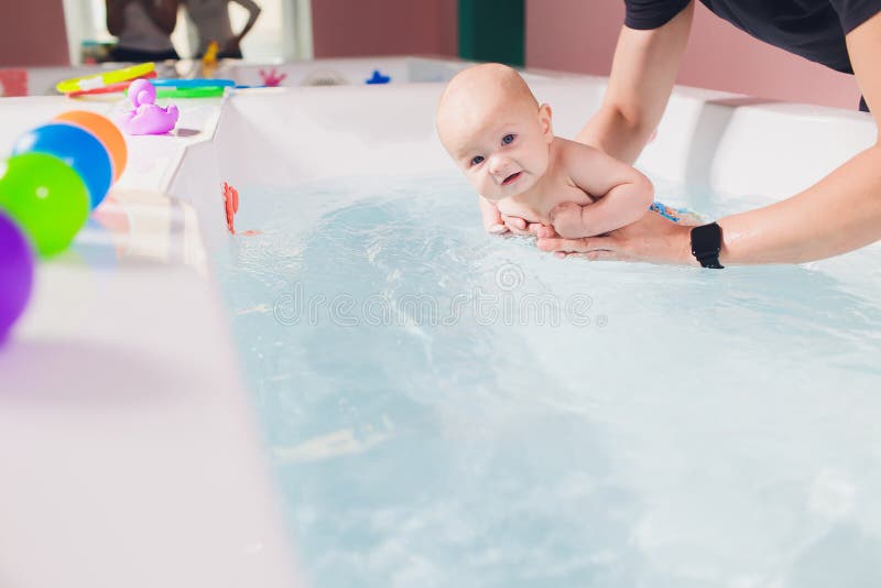 A Father Helps is Infant Boy during Swimming Lessons in the Pool. Stock ...