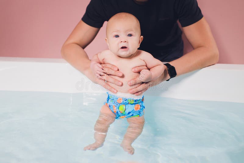 A Father Helps is Infant Boy during Swimming Lessons in the Pool. Stock ...