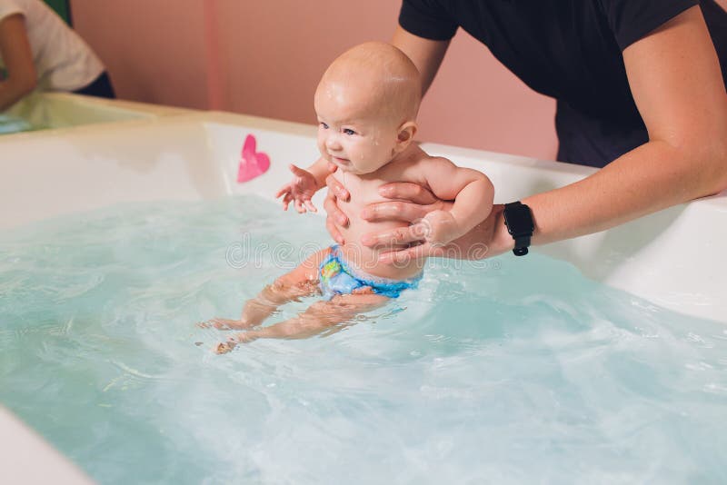 A Father Helps is Infant Boy during Swimming Lessons in the Pool. Stock ...
