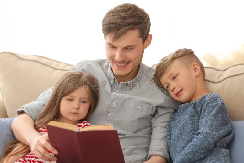 Father and His Children Reading Book Together at Home Stock Photo ...