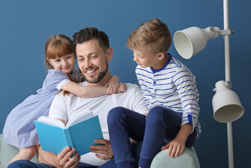 Father and His Children Reading Book Together at Home Stock Photo ...