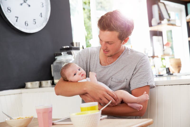 Father Holding Newborn Baby Daughter at Kitchen Table Stock Photo ...