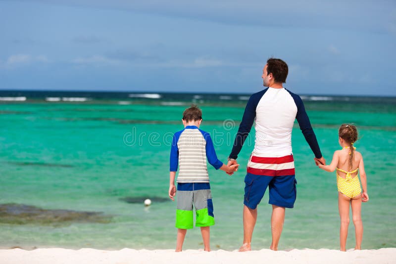 Father and Son Running Along Beach Together Wearing Swimming Costumes ...