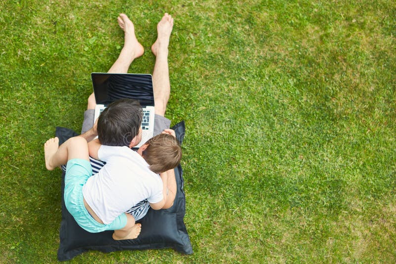 Father at Laptop Computer on Grass with Child Stock Photo - Image of ...