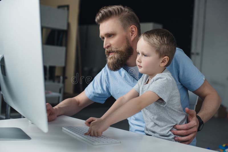 Father and Little Son Looking at Computer Screen while Using Computer ...