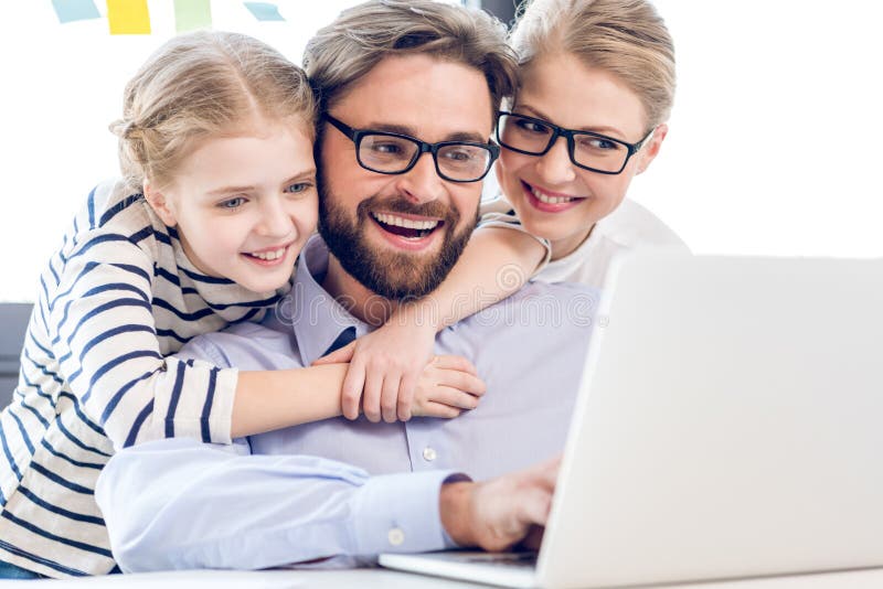 Father, Mother and Daughter Hugging and Using Laptop in Office Stock ...
