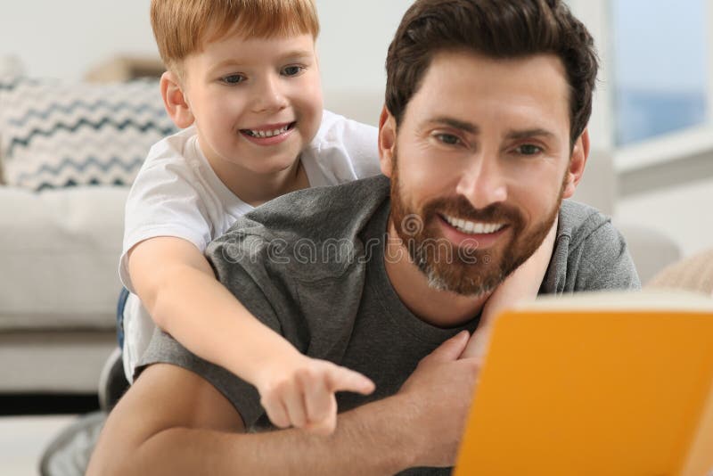 Father Reading Book with His Child on Floor at Home, Closeup Stock ...