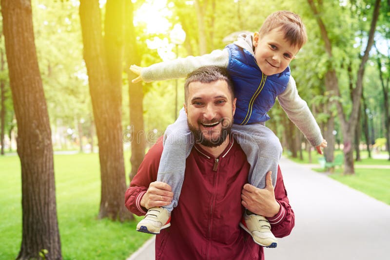 Father Riding His Small Son on Shoulders in Park on Sunny Day Stock ...