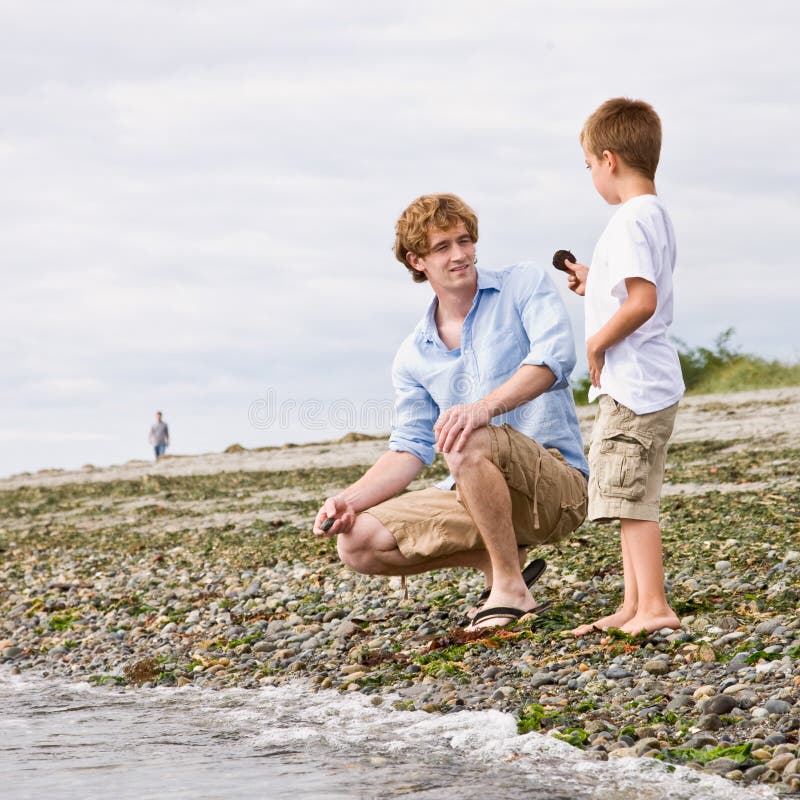 Father and Son Gathering Rocks at Beach Stock Photo - Image of hurling ...