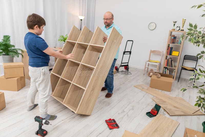A Father and Son Lift a Folding Bookcase Upright. Stock Image - Image ...