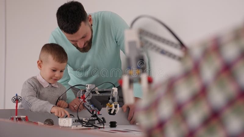 Father and Son Play with Programmed Robots in the School of Robotics ...